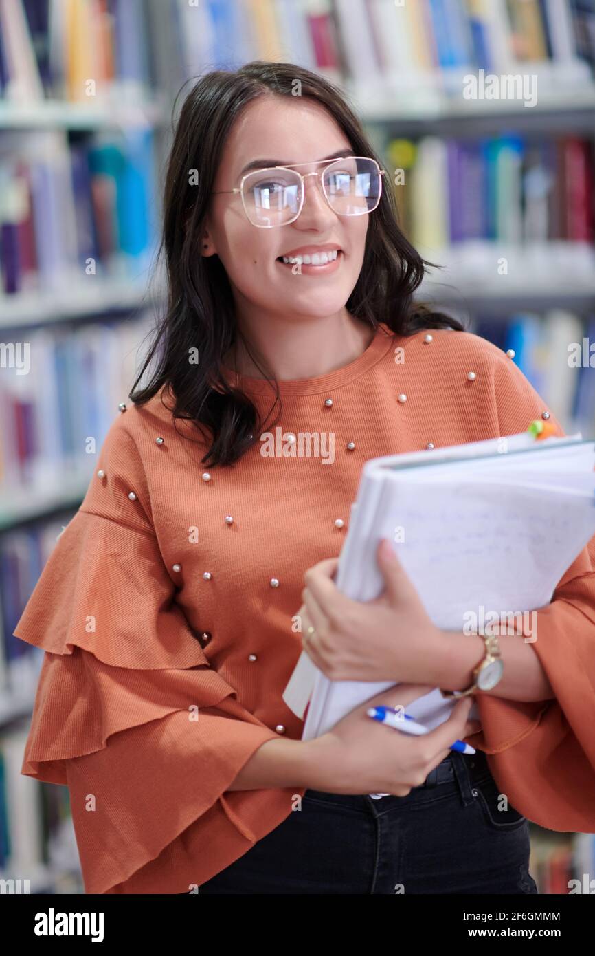 Reading a book in library. Young attractive librarian reading a book ...