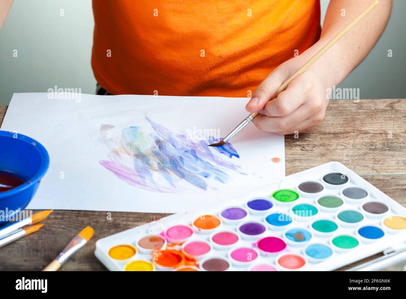 A caucasian boy is drawing an abstract picture on a white paper using a ...