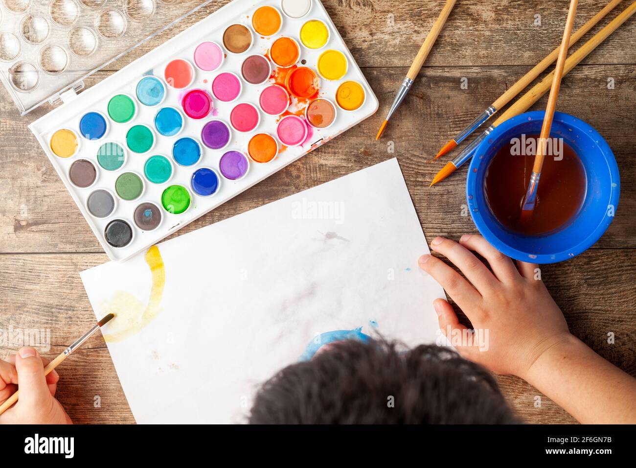 A caucasian boy is drawing an abstract picture on a white paper using a ...