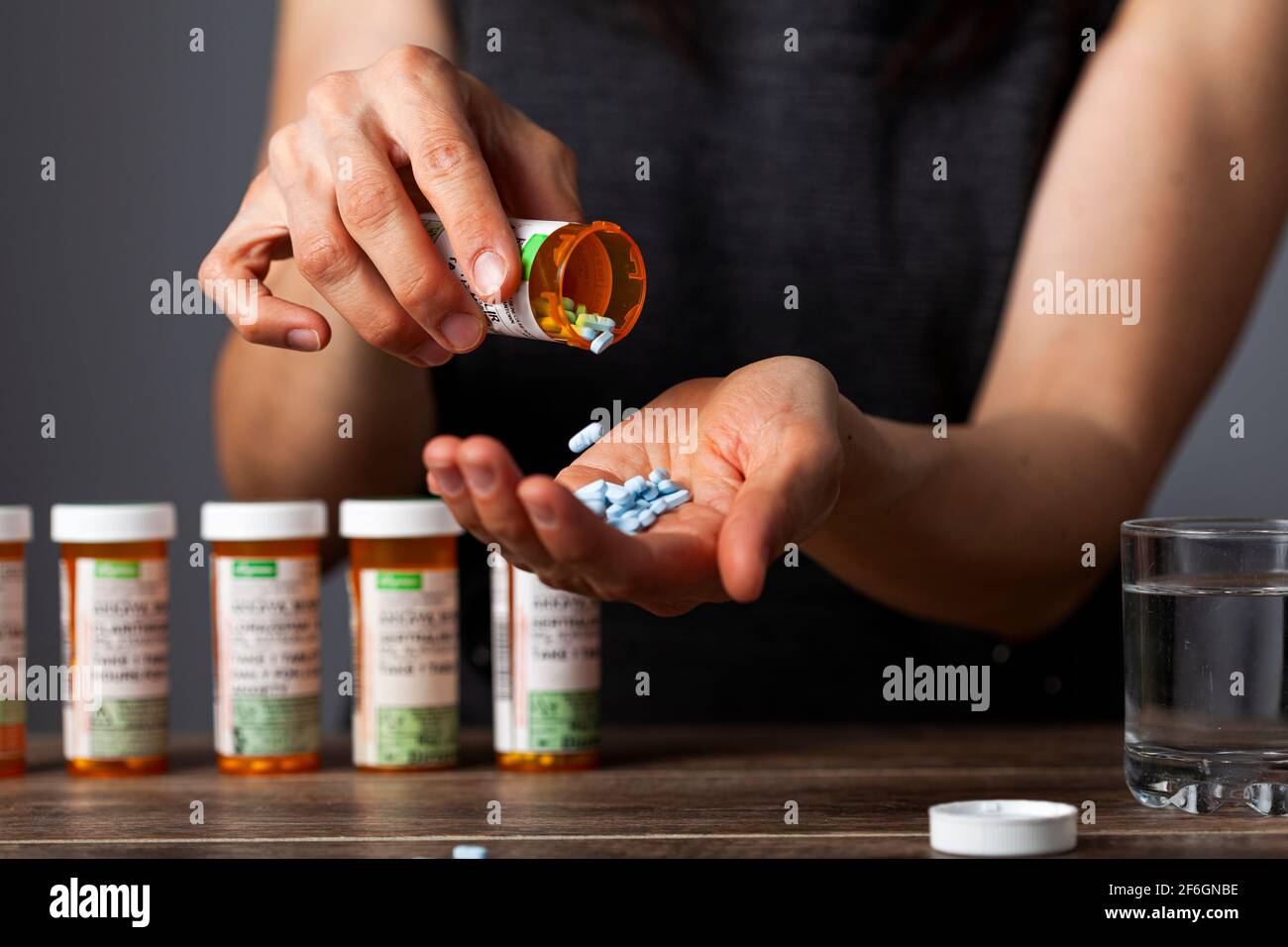 a young depressed woman is taking pills out of the medication bottle ...