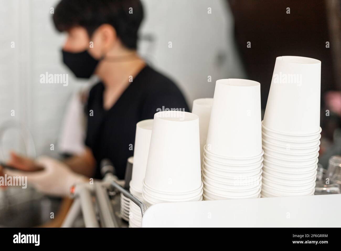 A lot of white disposable paper cups on coffee machine with cofe shop ...