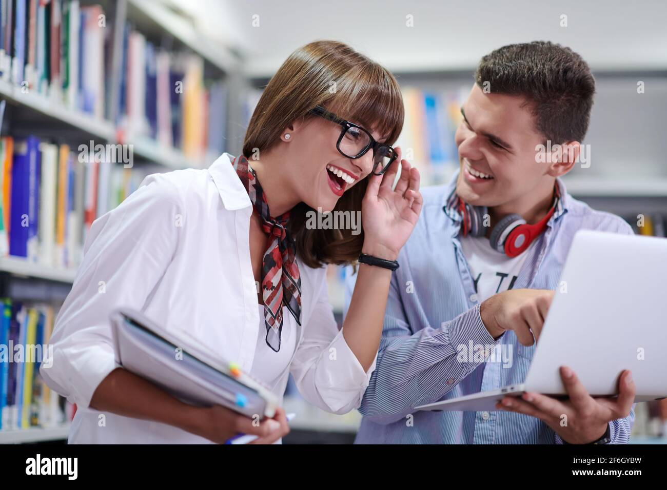 Two students using modern technology stand in the school library Stock ...