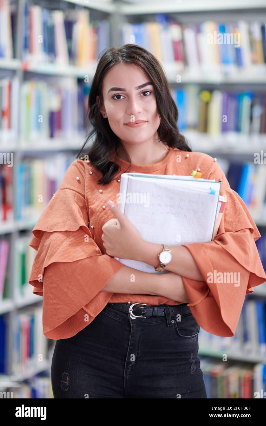 Reading a book in library. Young attractive librarian reading a book ...