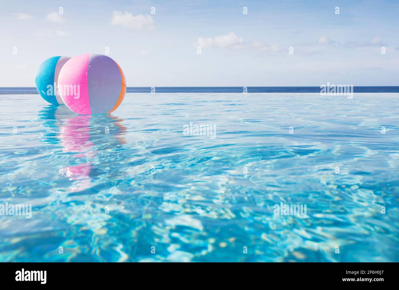 Beach balls floating on water in infinity pool Stock Photo - Alamy
