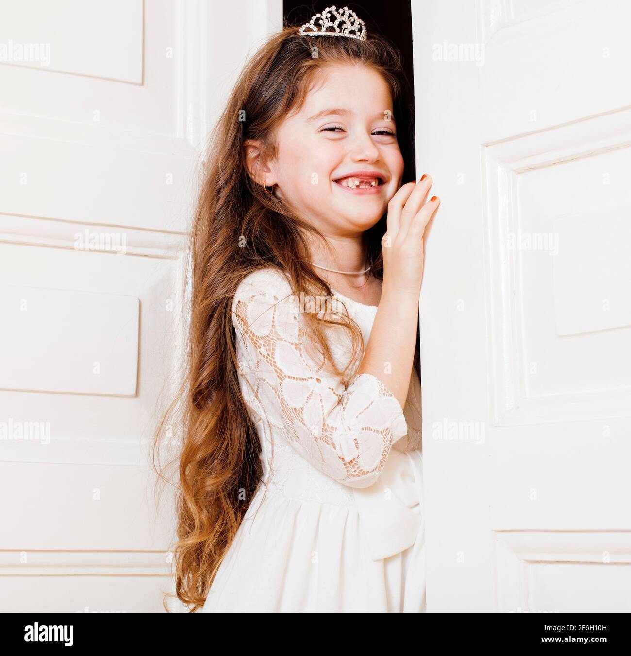 little cute girl at home, opening door well-dressed in white dress ...