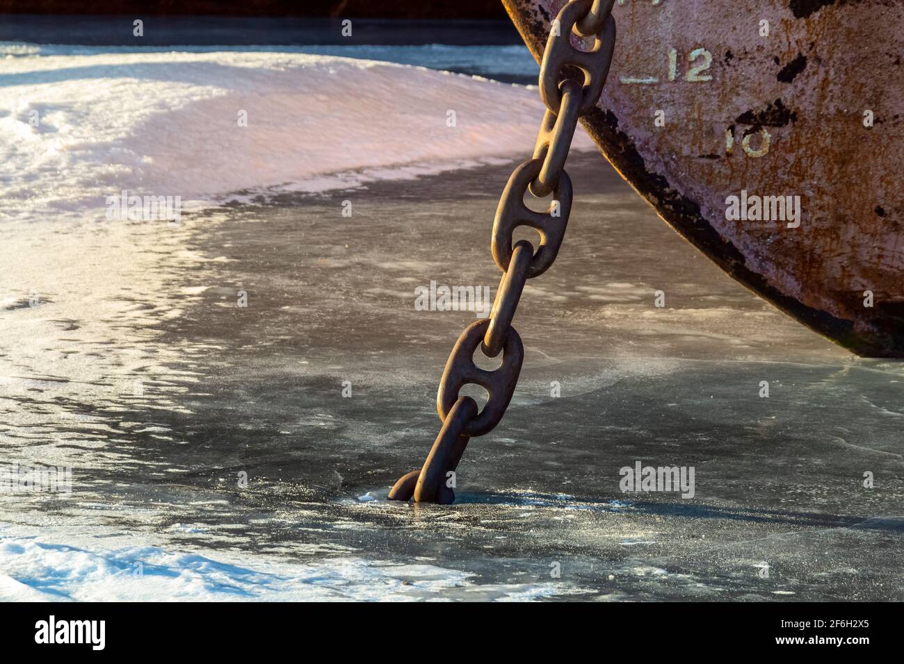 A rusty chain of an old anchor frozen into the ice Stock Photo - Alamy