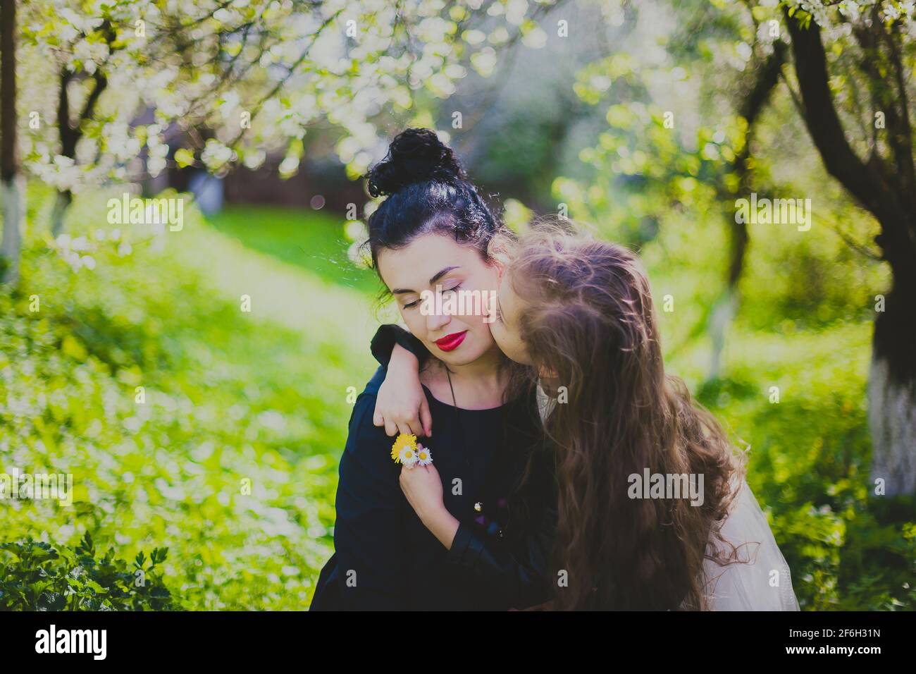 Little girl hugs her mother in the spring cherry garden Stock Photo - Alamy