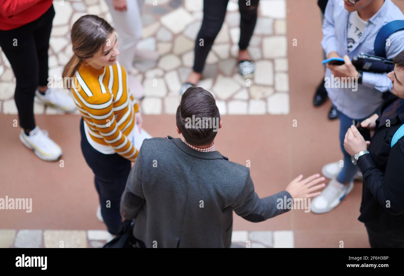 students in the hallway talk to their professor while waiting for ...