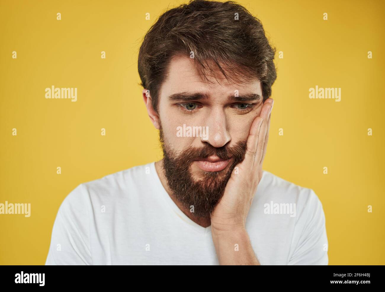 sad man on a yellow background in a white t-shirt beard model Stock ...