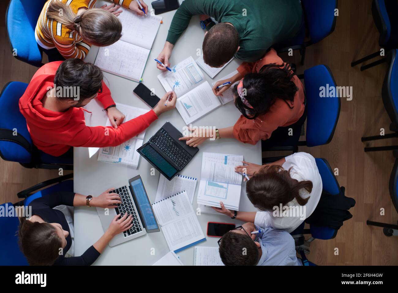 Top view of university students sitting at a table studying and working ...