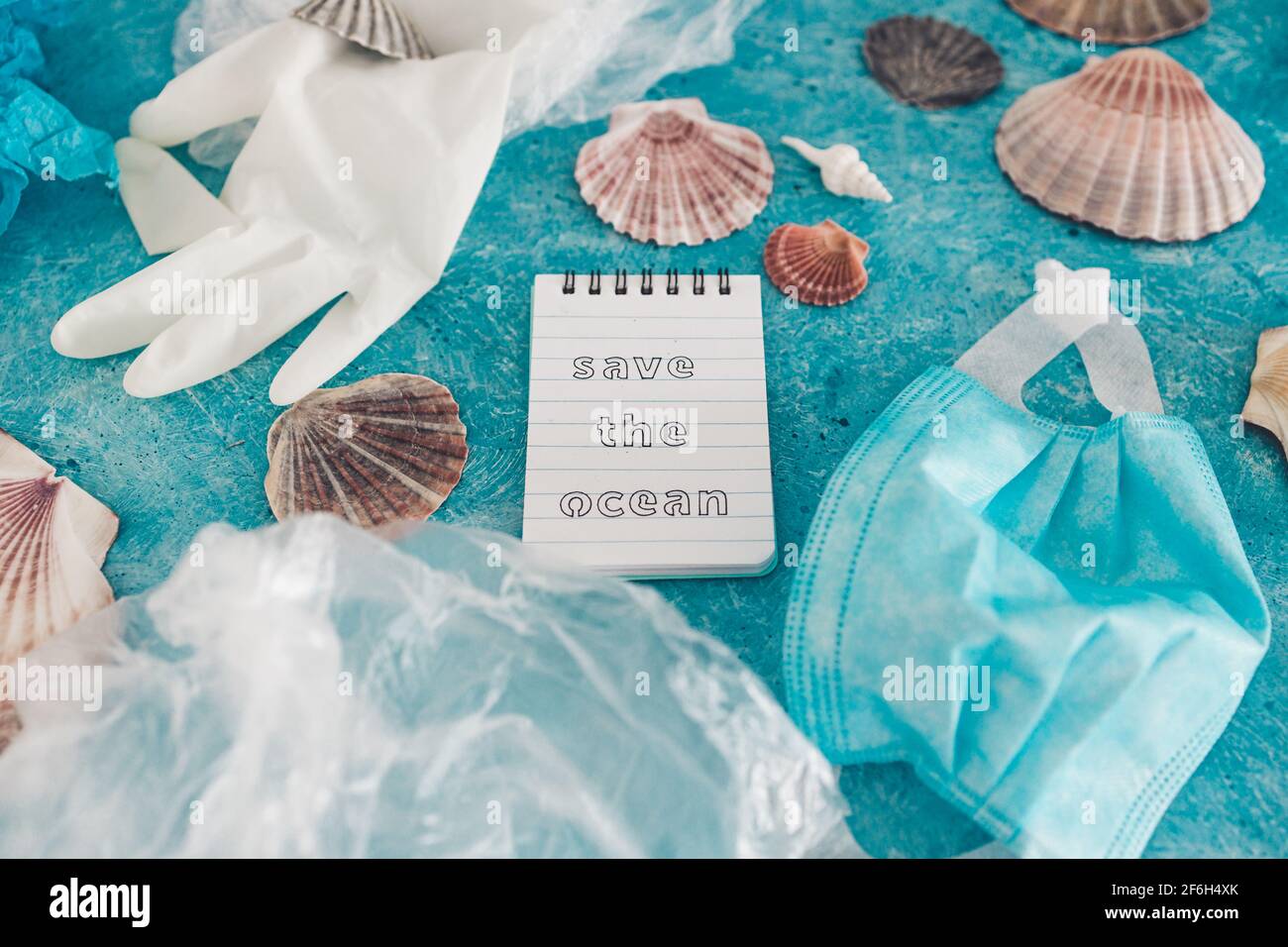 save the ocean text on blue bakground with sea shells and plastic ...