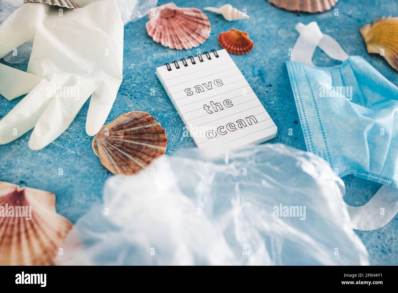 save the ocean text on blue bakground with sea shells and plastic ...