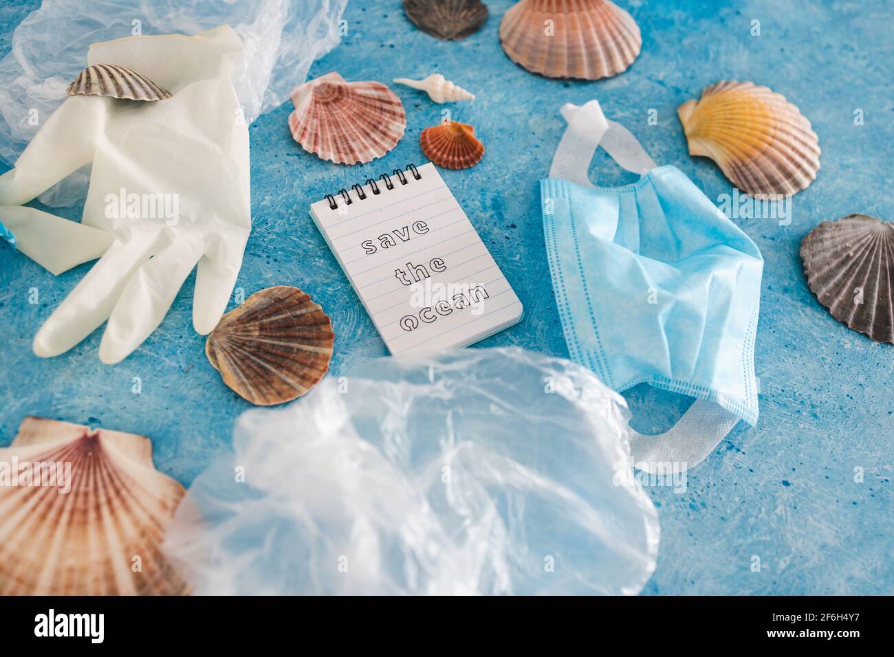 save the ocean text on blue bakground with sea shells and plastic ...