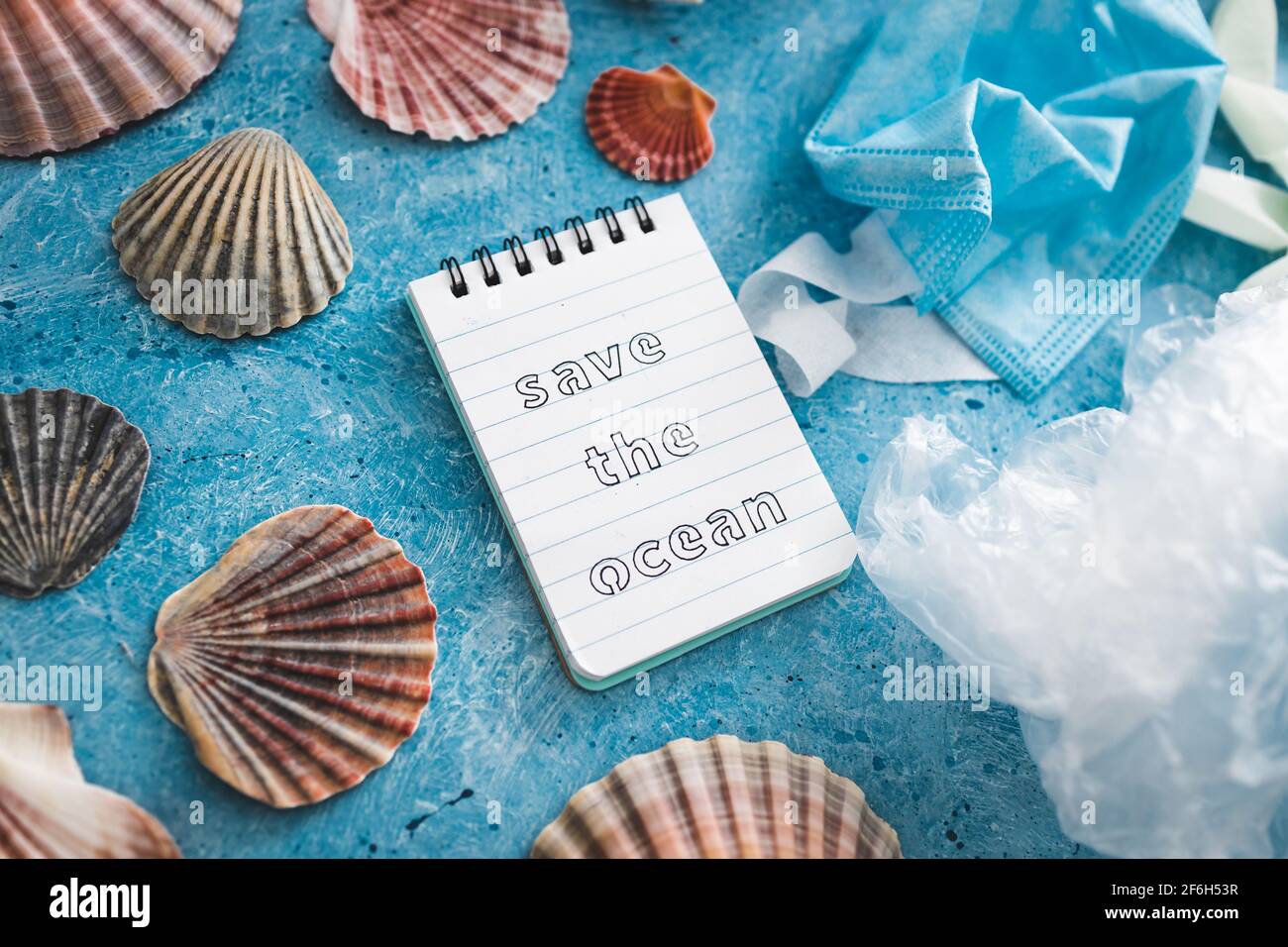 save the ocean text on blue bakground with sea shells and plastic ...