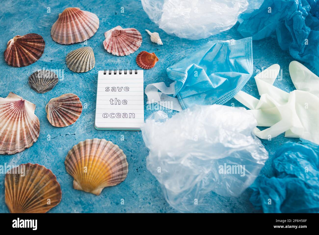 save the ocean text on blue bakground with sea shells and plastic ...