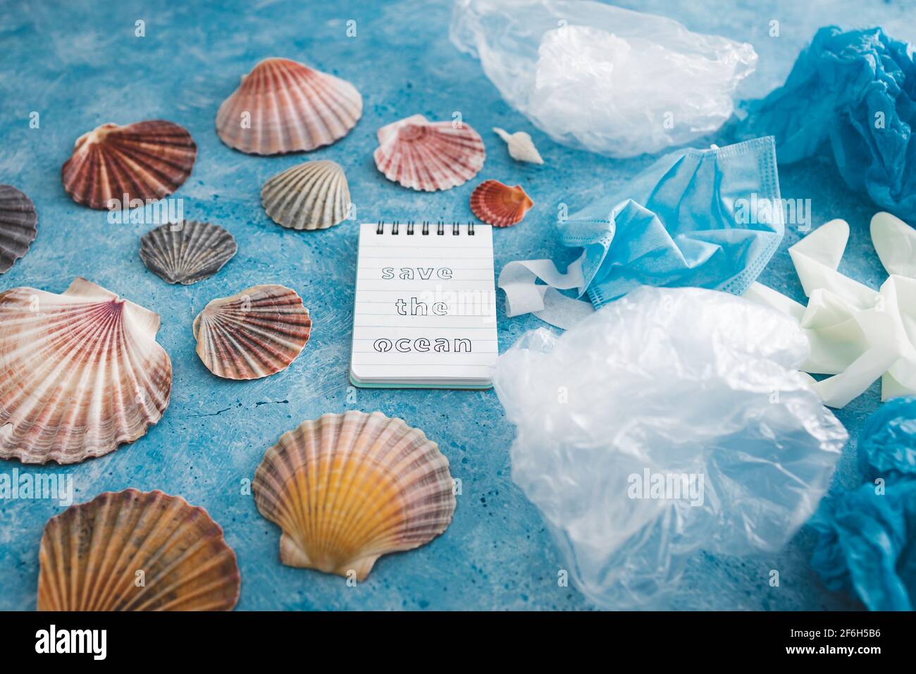 save the ocean text on blue bakground with sea shells and plastic ...