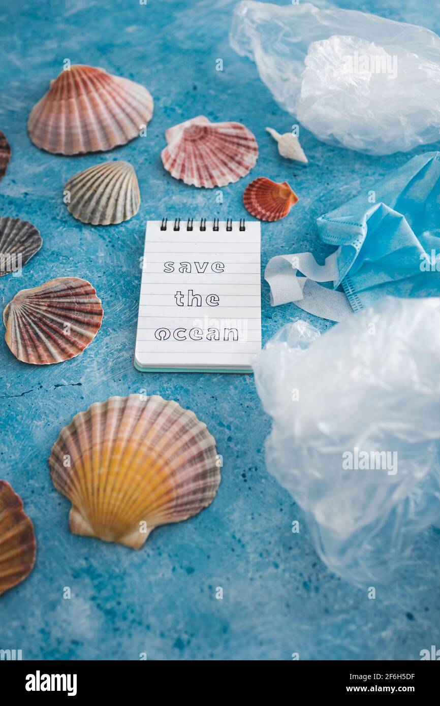 save the ocean text on blue bakground with sea shells and plastic ...