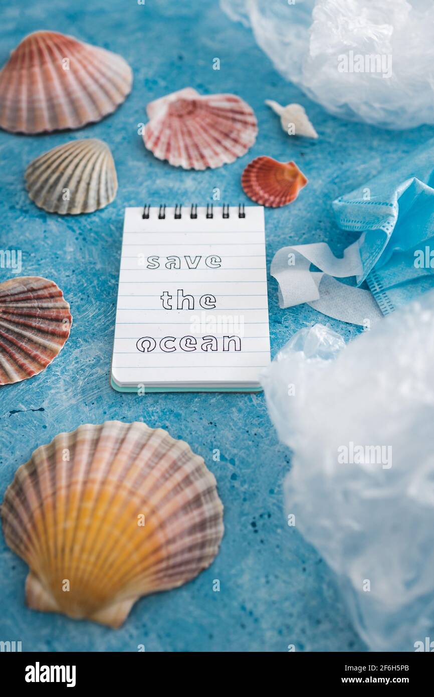 save the ocean text on blue bakground with sea shells and plastic ...