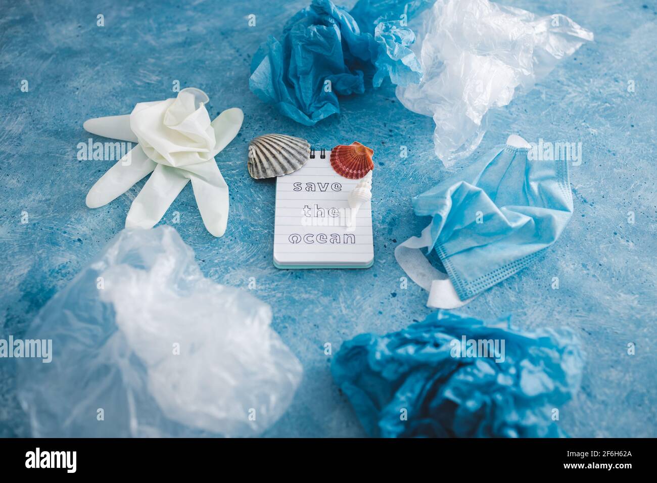 save the ocean text on blue bakground with sea shells and plastic ...