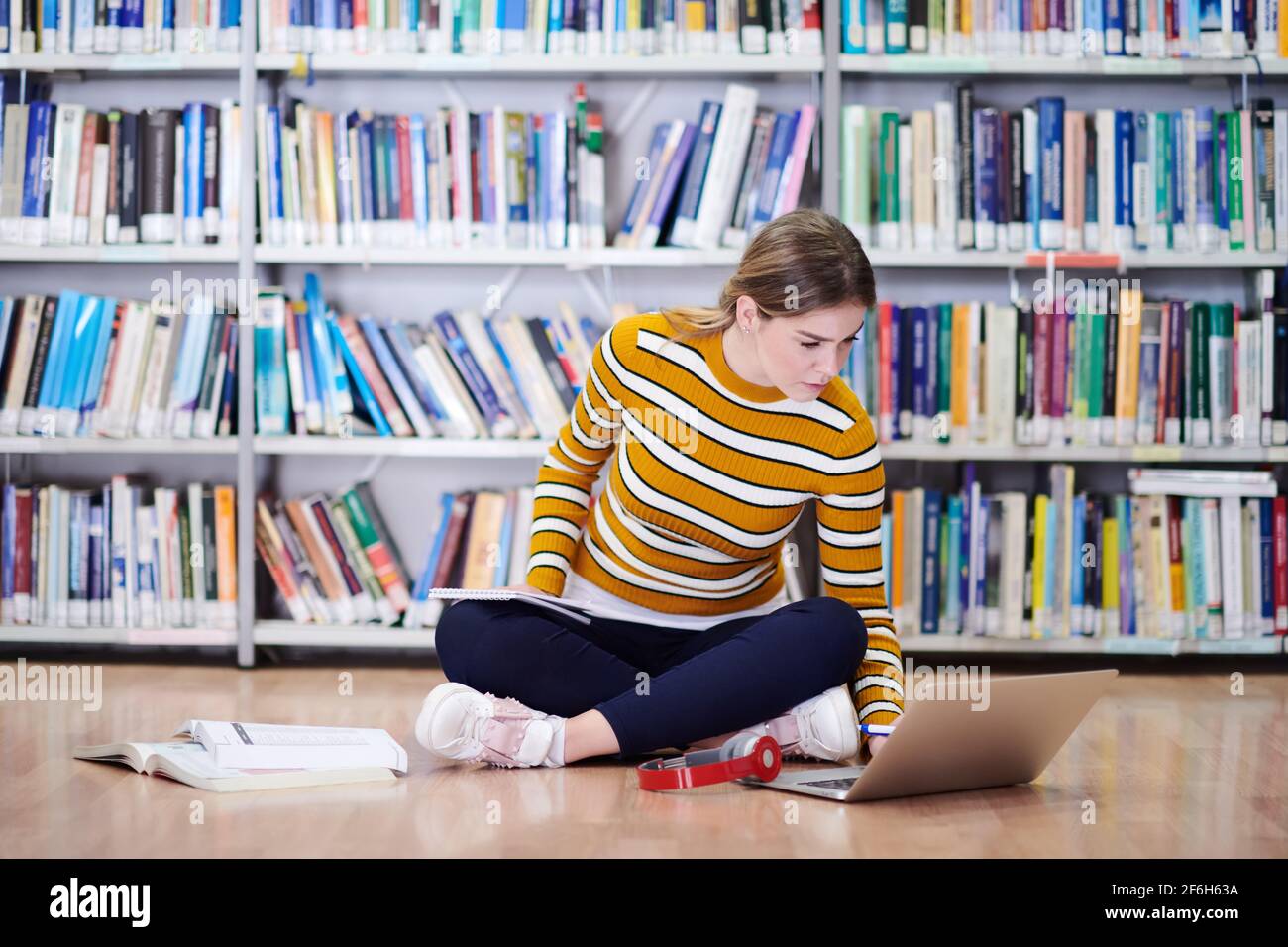 Woman student taking notes from a book at library. Young woman sitting ...