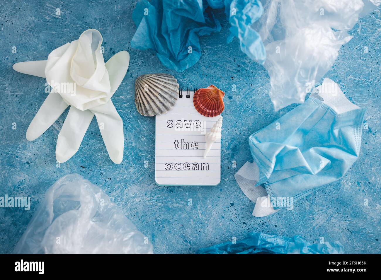 save the ocean text on blue bakground with sea shells and plastic ...