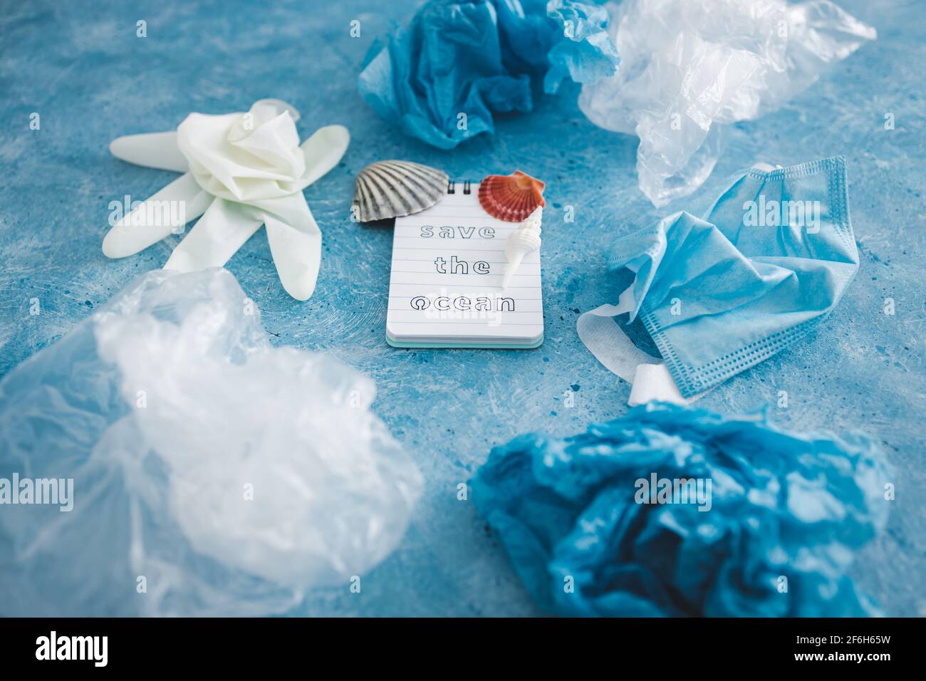 save the ocean text on blue bakground with sea shells and plastic ...
