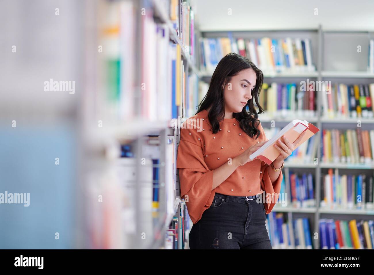 Reading a book in library. Young attractive librarian reading a book ...