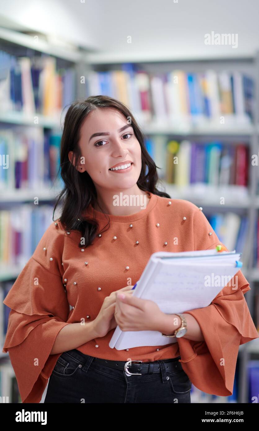 Reading a book in library. Young attractive librarian reading a book ...