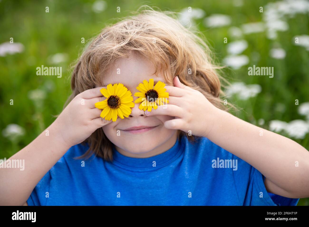 Spring kid. Funny little boy with daisy in eyes Stock Photo - Alamy