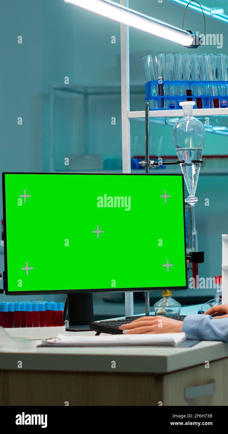 Biochemist sitting at workplace in laboratory using green mock-up ...