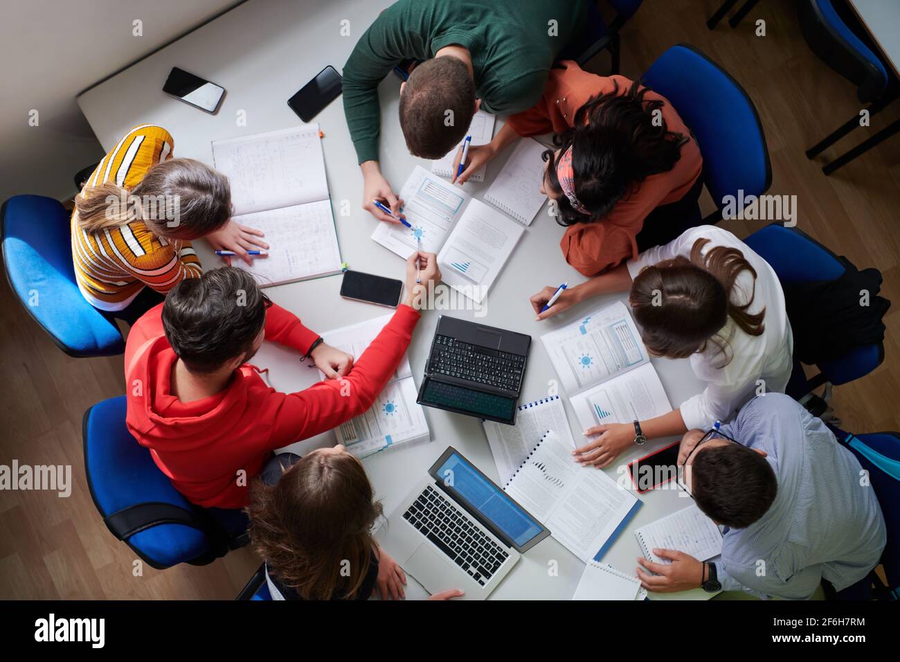 Top view of university students sitting at a table studying and working ...