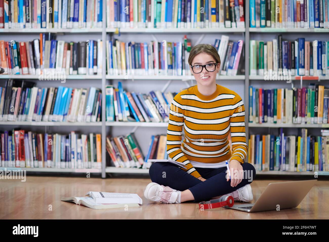 Woman student taking notes from a book at library. Young woman sitting ...