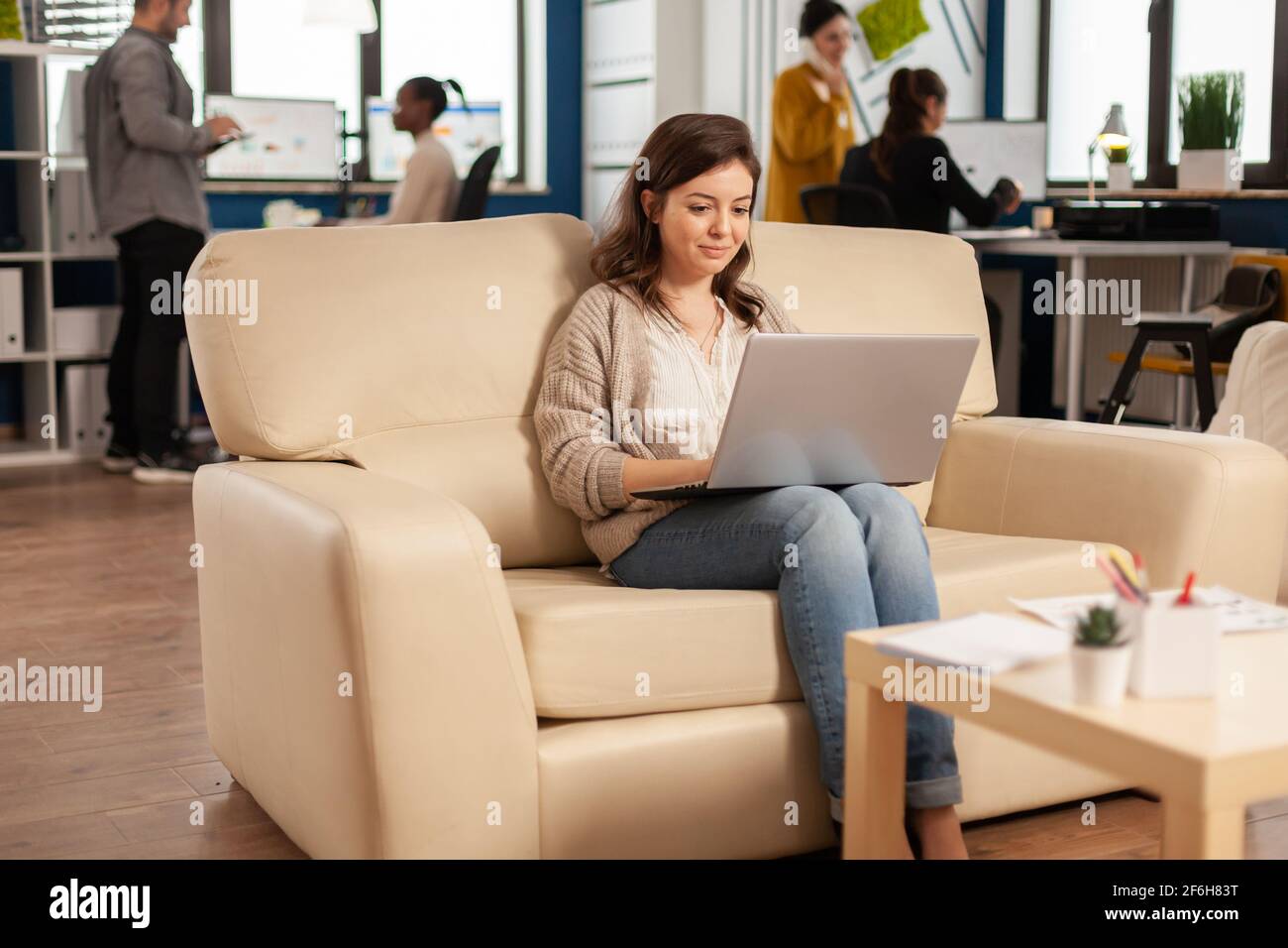 Focused manager reading tasks on laptop and typing sitting on couch in ...