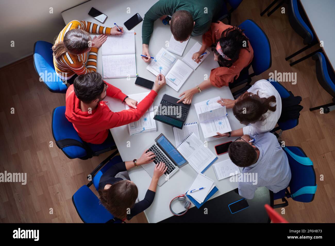 Top view of university students sitting at a table studying and working ...
