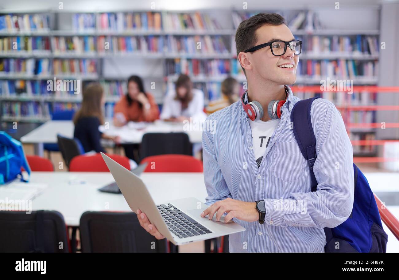a young student with glasses stands in the school library with a ...