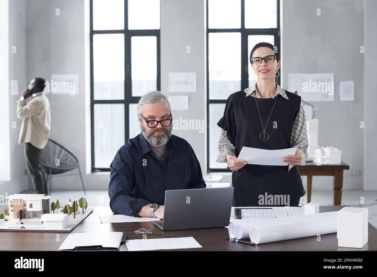 Portrait of successful architects looking at camera while working with ...