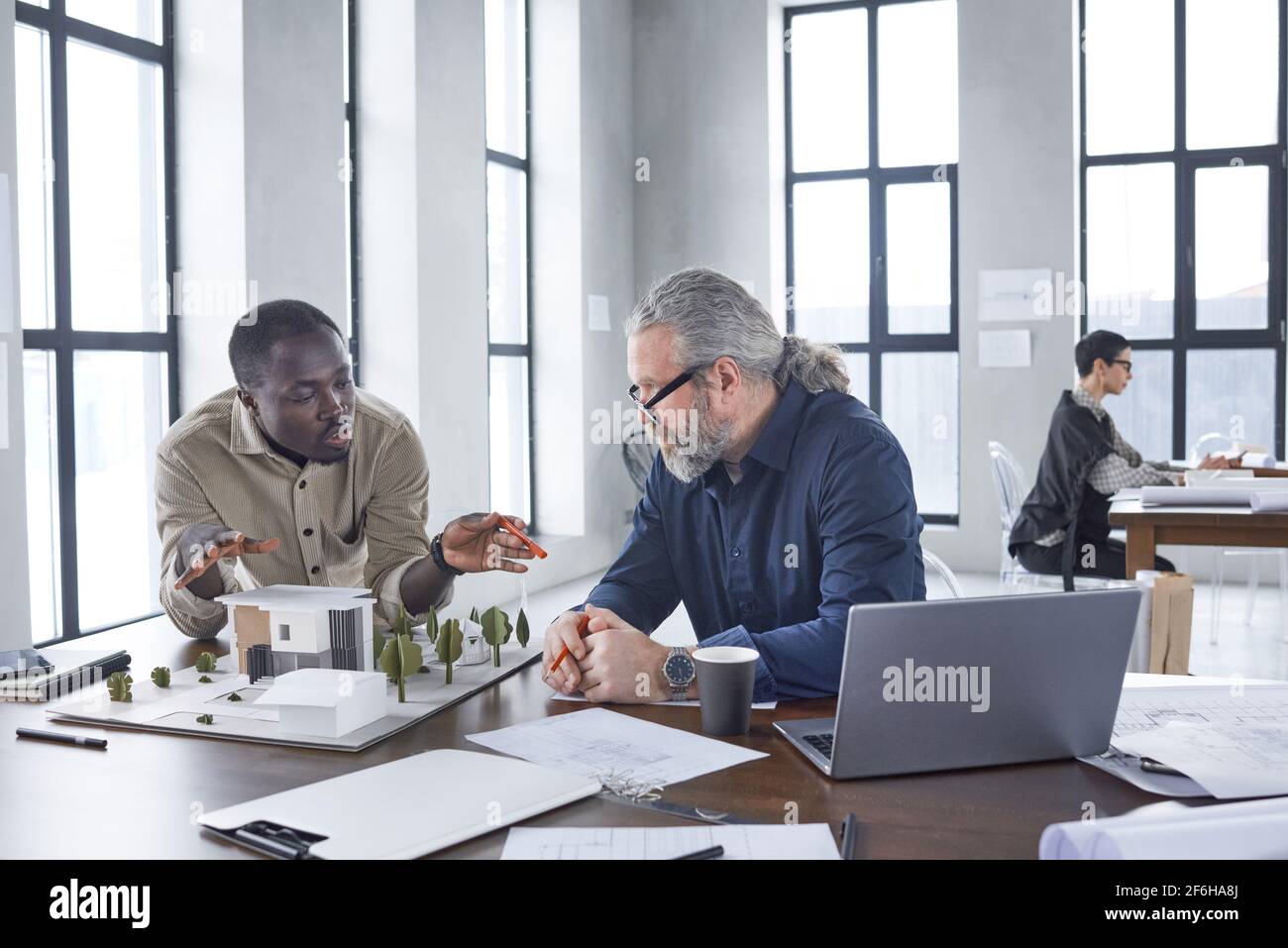 Two architects sitting at the table with model of new building and ...
