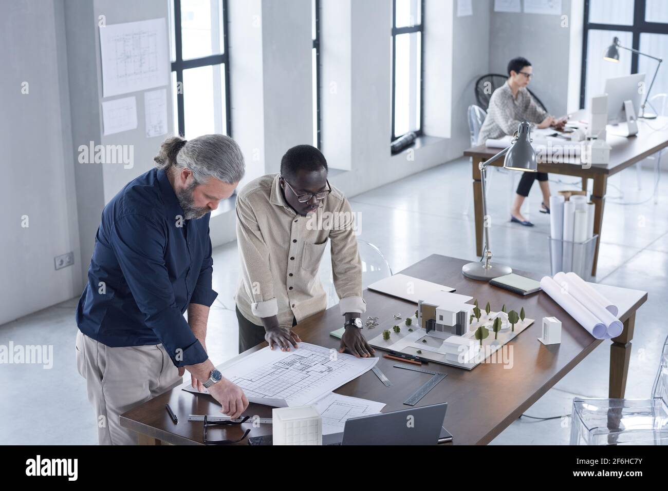 Two architects standing near the table with model of buildings and ...