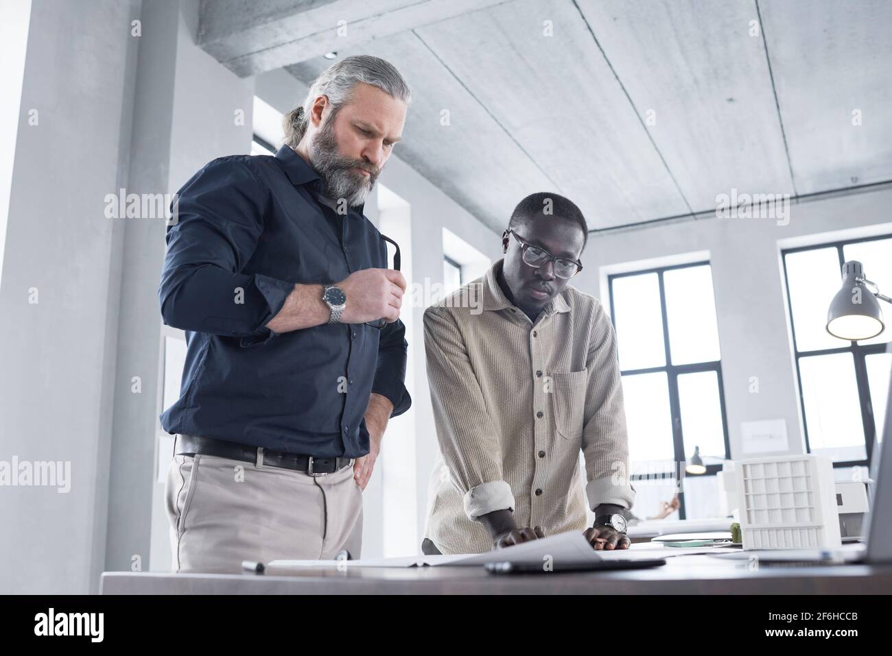 Two architects working in team standing near the table with blueprints ...