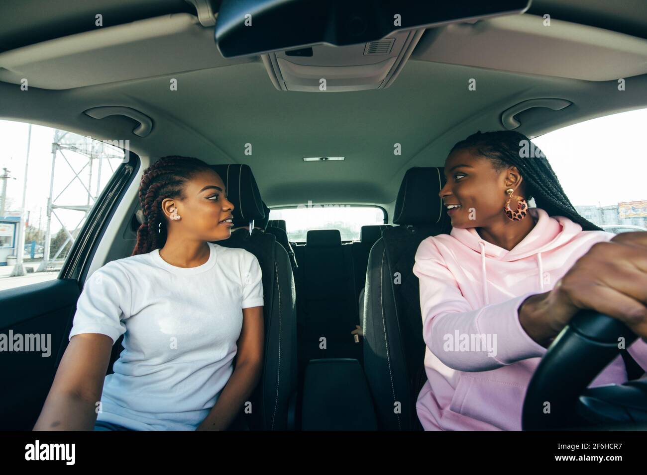 Two african woman friends talking each other in the car while driving ...