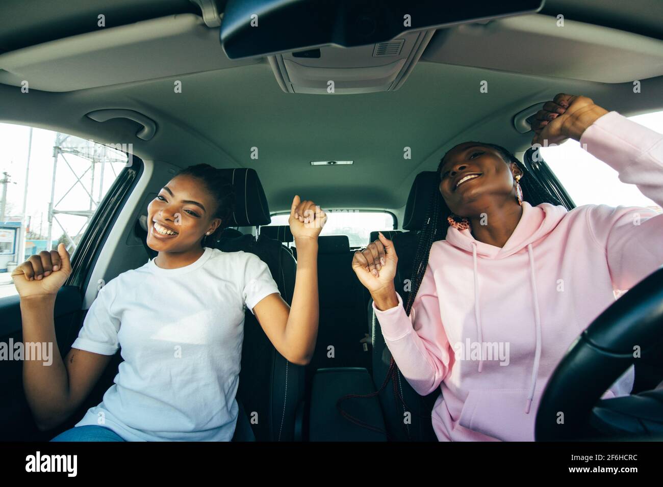 Two African Woman Dancing In The Car While Driving Car On The Street