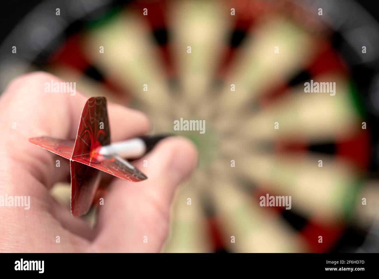 Close-up of man hand holding red dart at middle of dartboard, which is ...