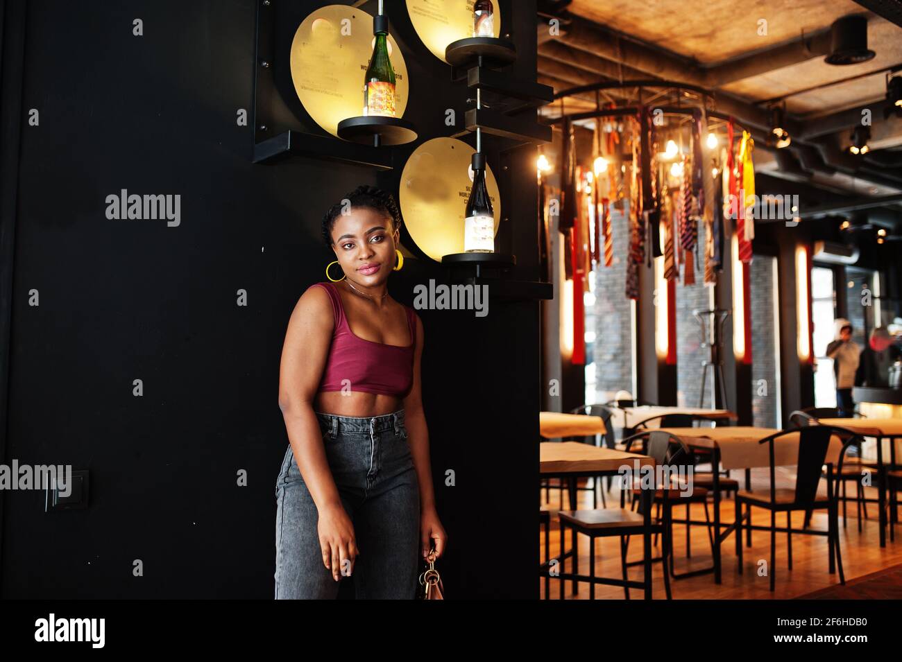 African woman in red marsala top and jeans posed indoor Stock Photo - Alamy