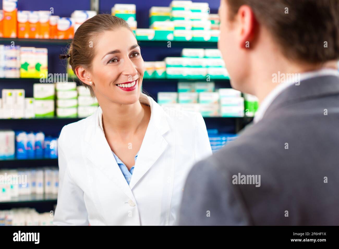 Female pharmacist consulting a customer in pharmacy Stock Photo - Alamy