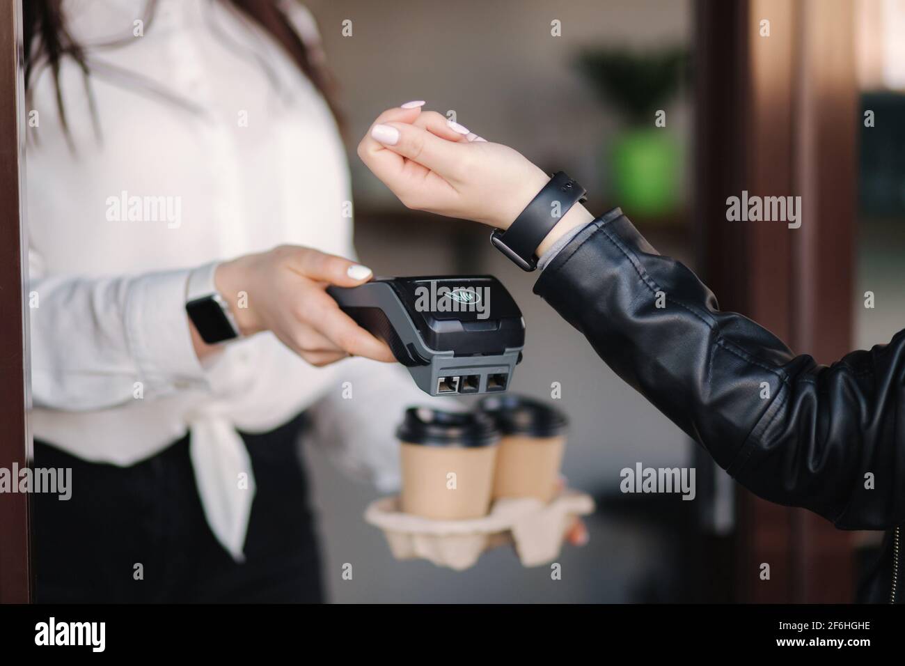 Female customer making wireless or contactless payment using smartwatch ...