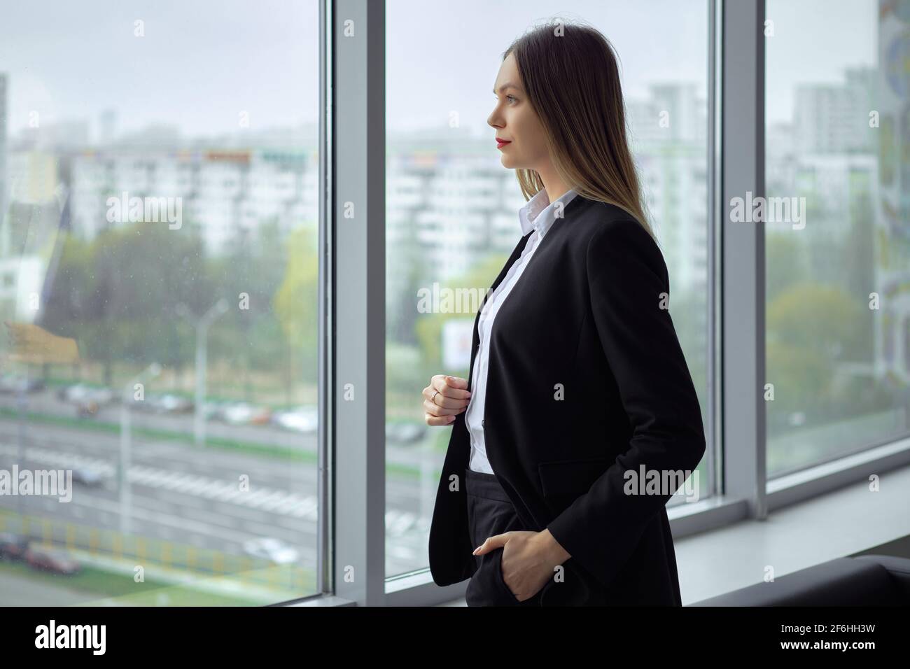Beautiful business lady standing thoughtfully by the window Stock Photo ...