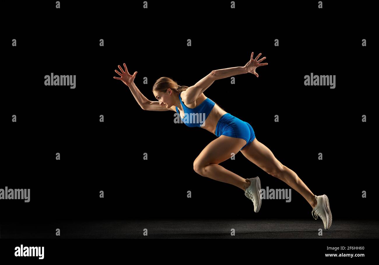 Active woman, track athlete training isolated over black studio ...