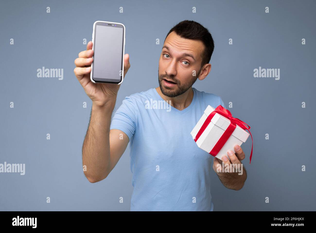 Handsome positive brunette adult man with beard isolated over blue ...