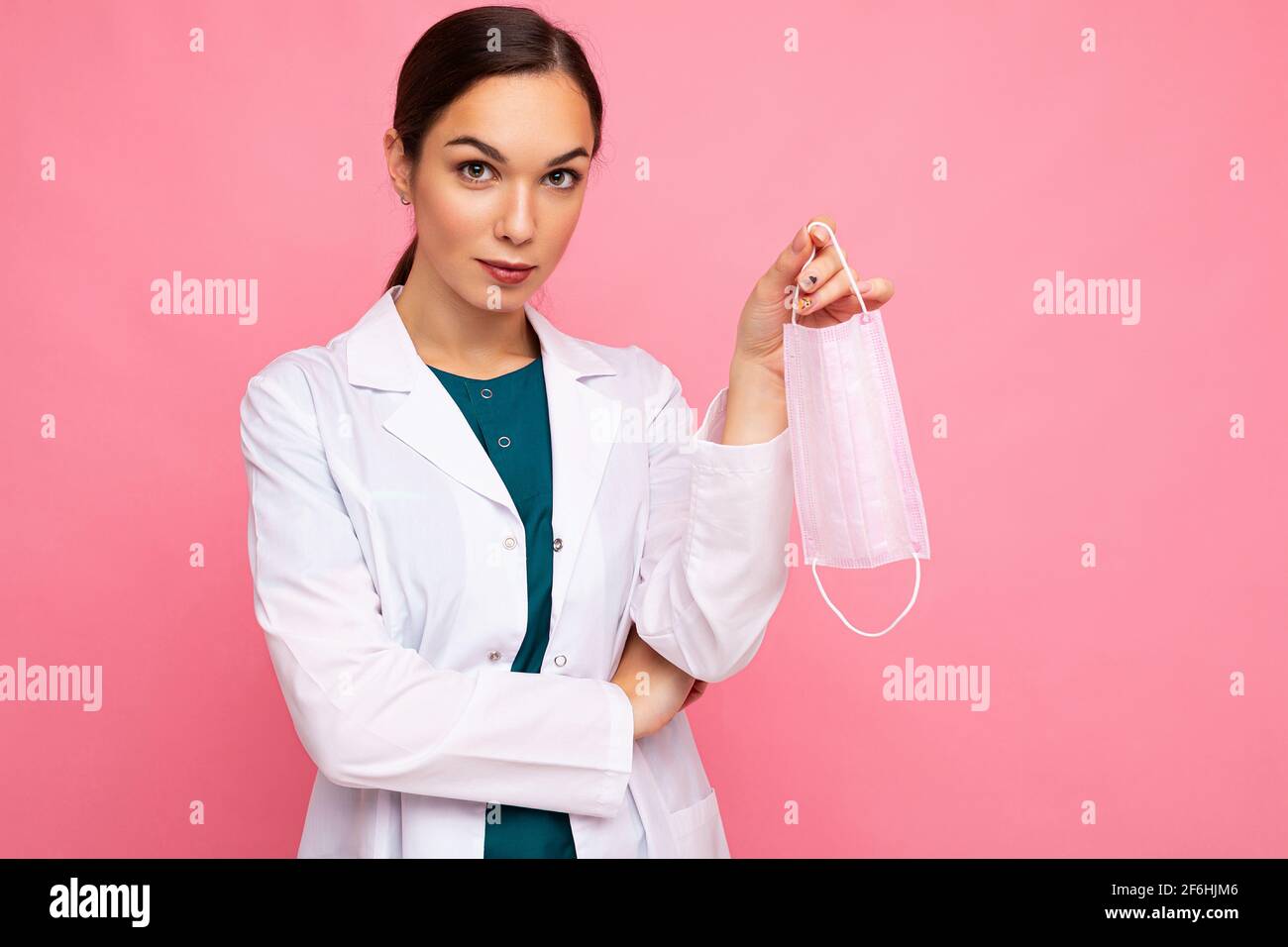Portrait of an attractive young female doctor in white coat holding ...