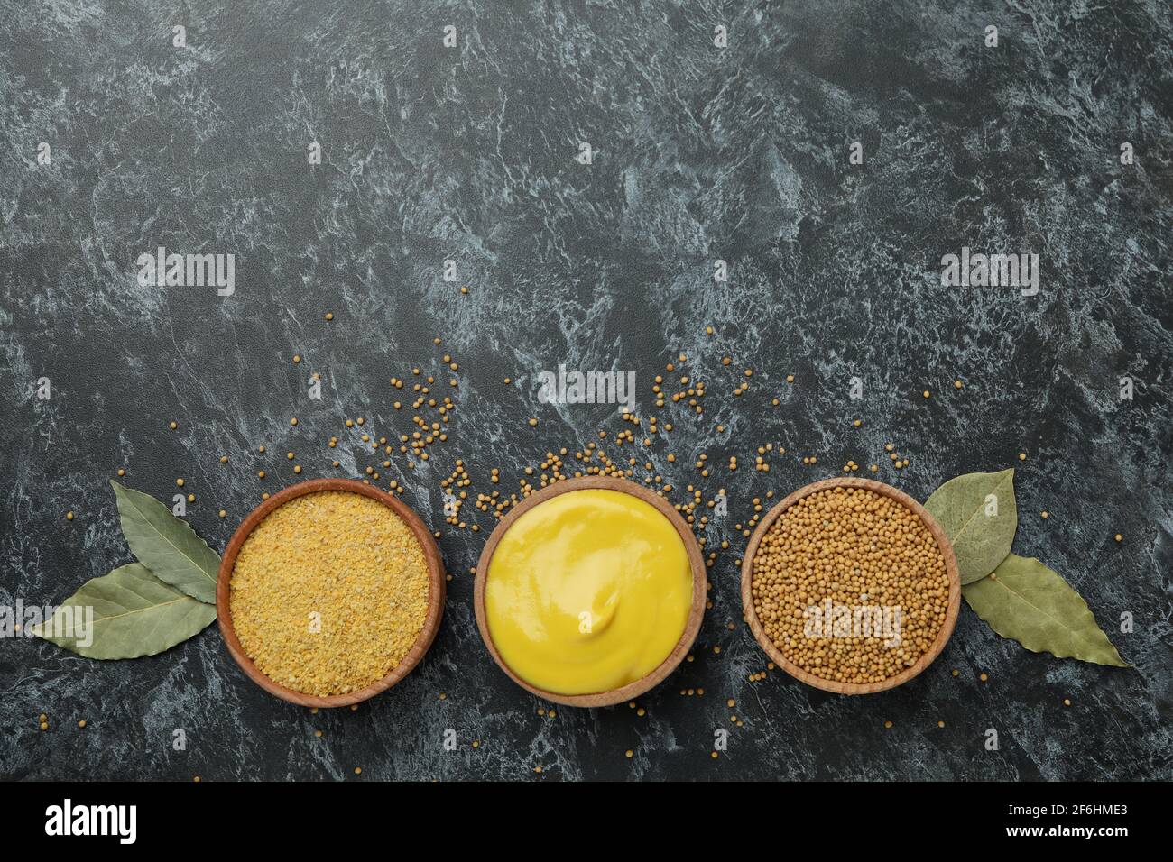 Bowls with mustard seeds, sauce and powder on black smoky background ...